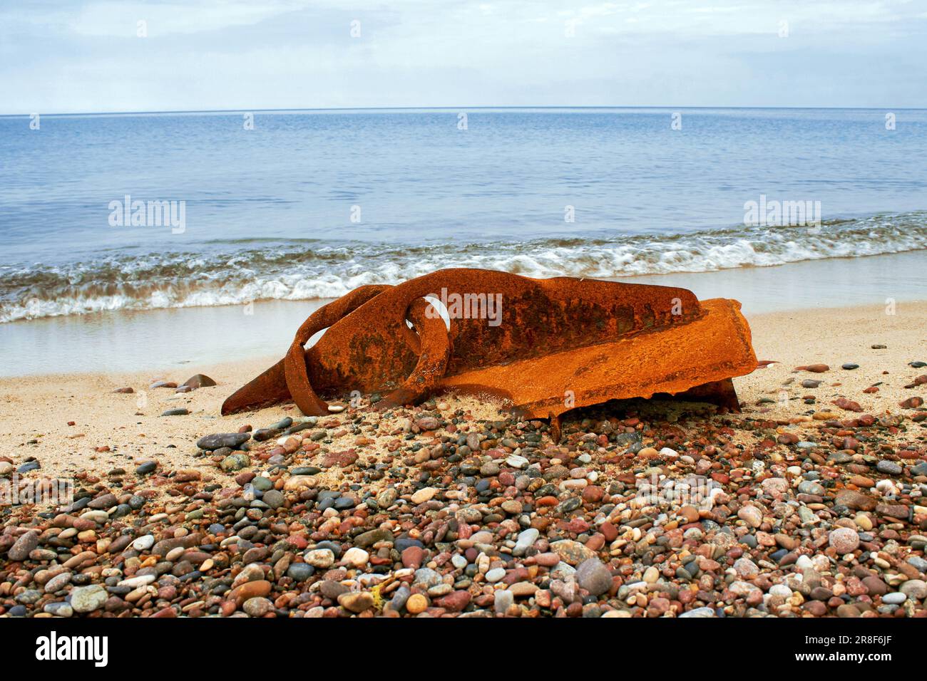 A rusty metal fragment of a ship's side thrown onto the seashore ...