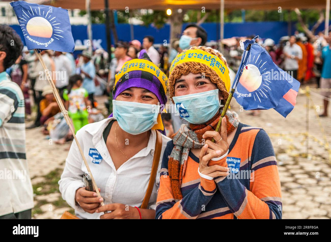 Portrait of 2 Sam Rainsy supporters wearing face masks & waving flags ...
