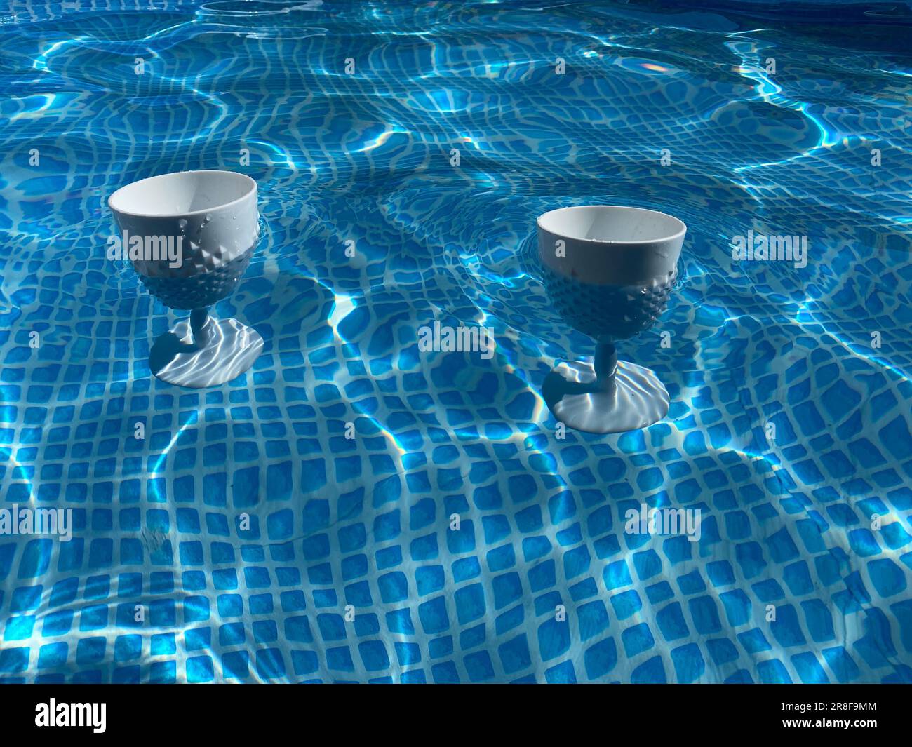 Two white ceramic cups floating in a pool Stock Photo - Alamy