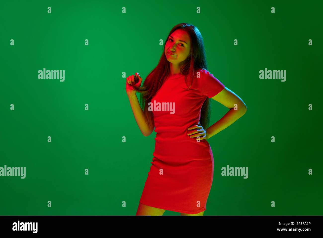 Portrait of young brunette woman in red dress standing with unpleasant ...