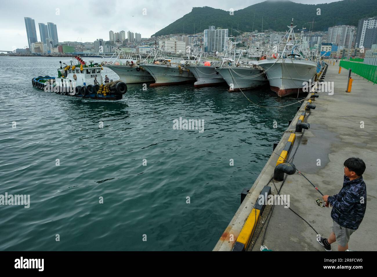 Busan, South Korea - May 28, 2023: A man fishing in the Busan harbor ...