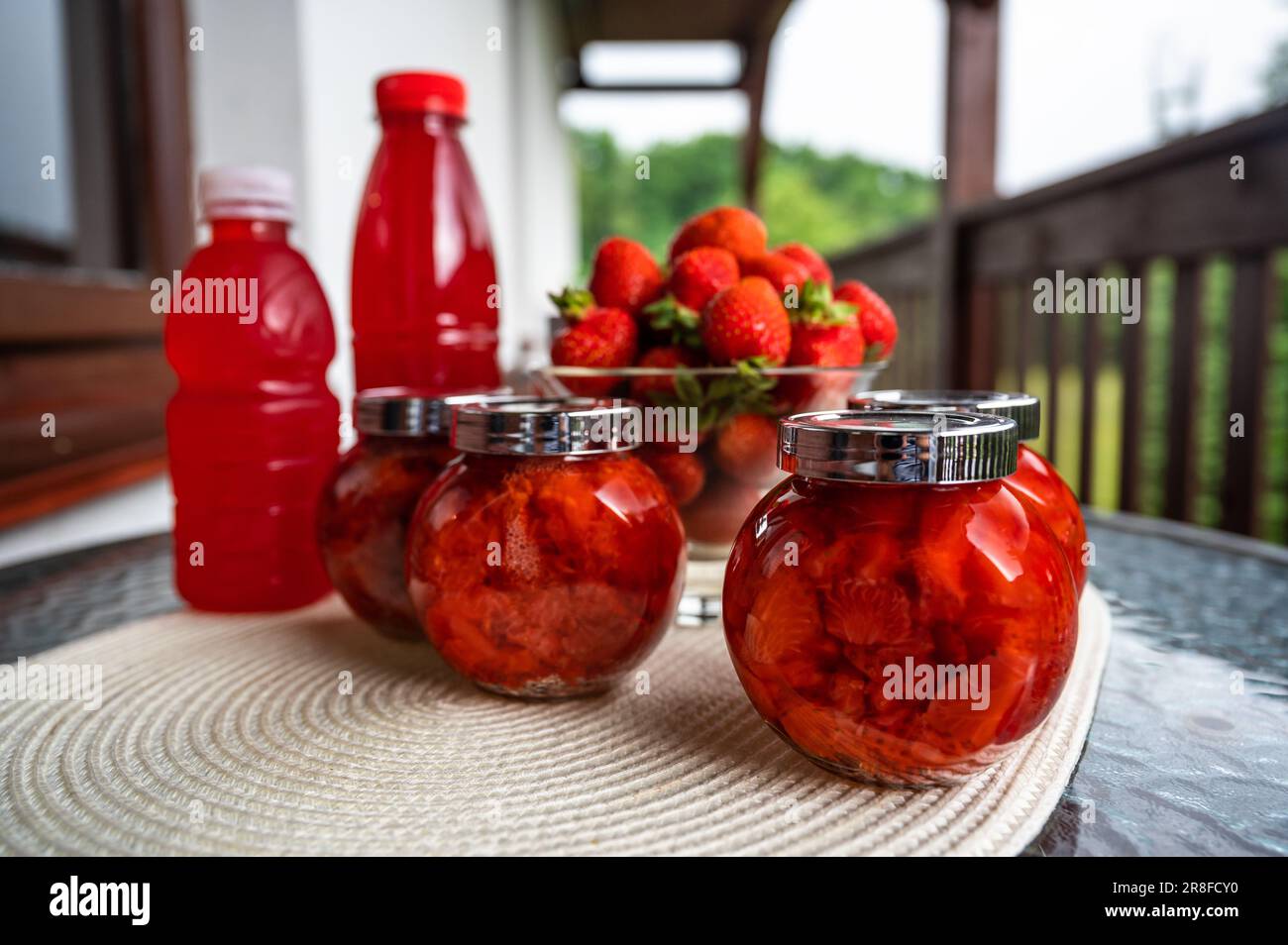 Jar with strawberry jam, bottle with sirup and raw strawberry on table ...