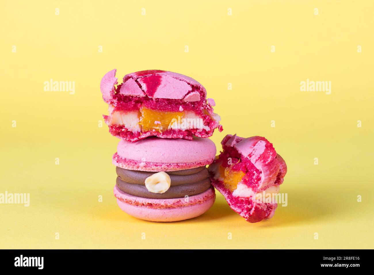Pink macarons with hazelnuts, caramel and orange filling on bright ...