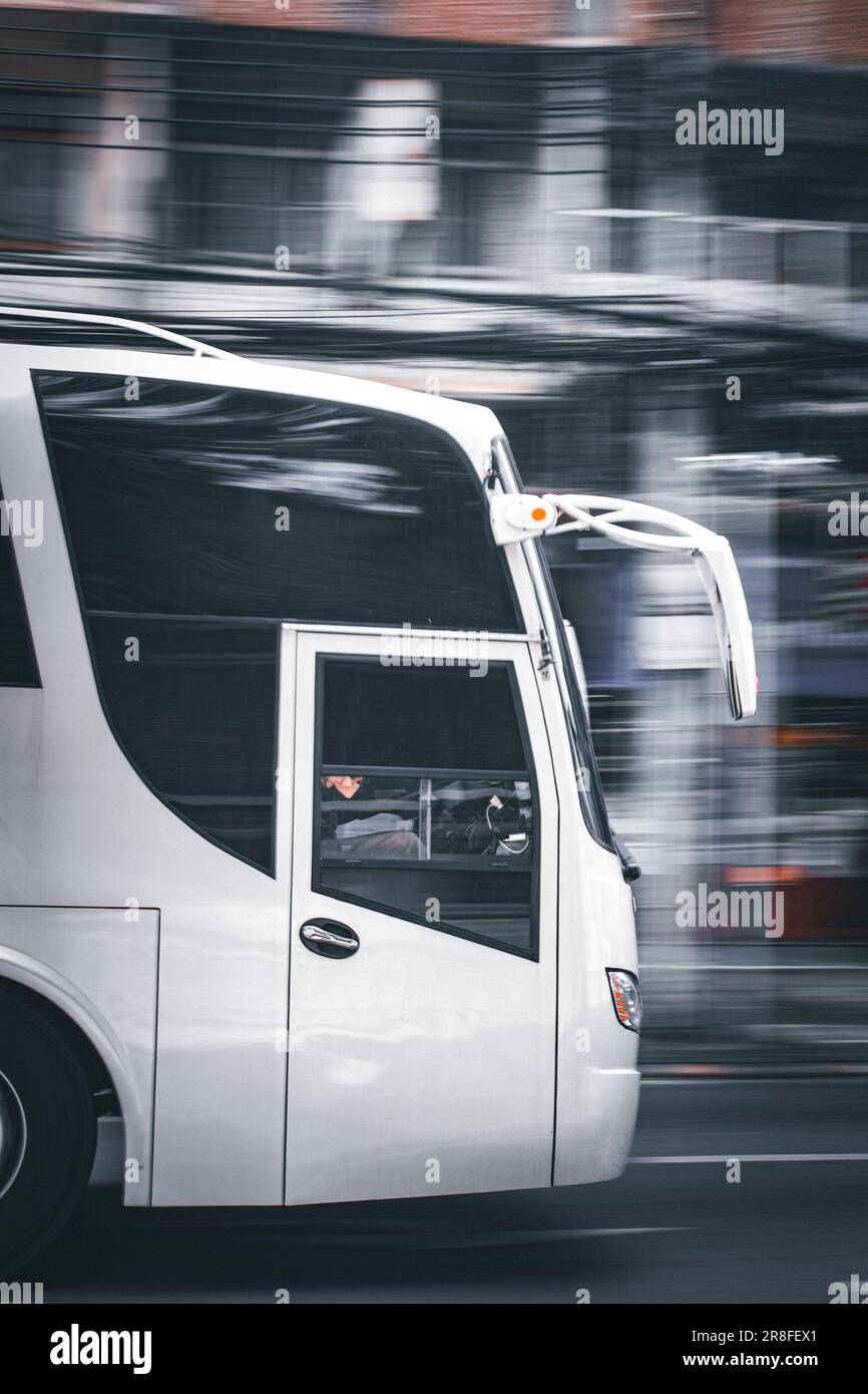 A white bus traveling down a busy city street Stock Photo - Alamy