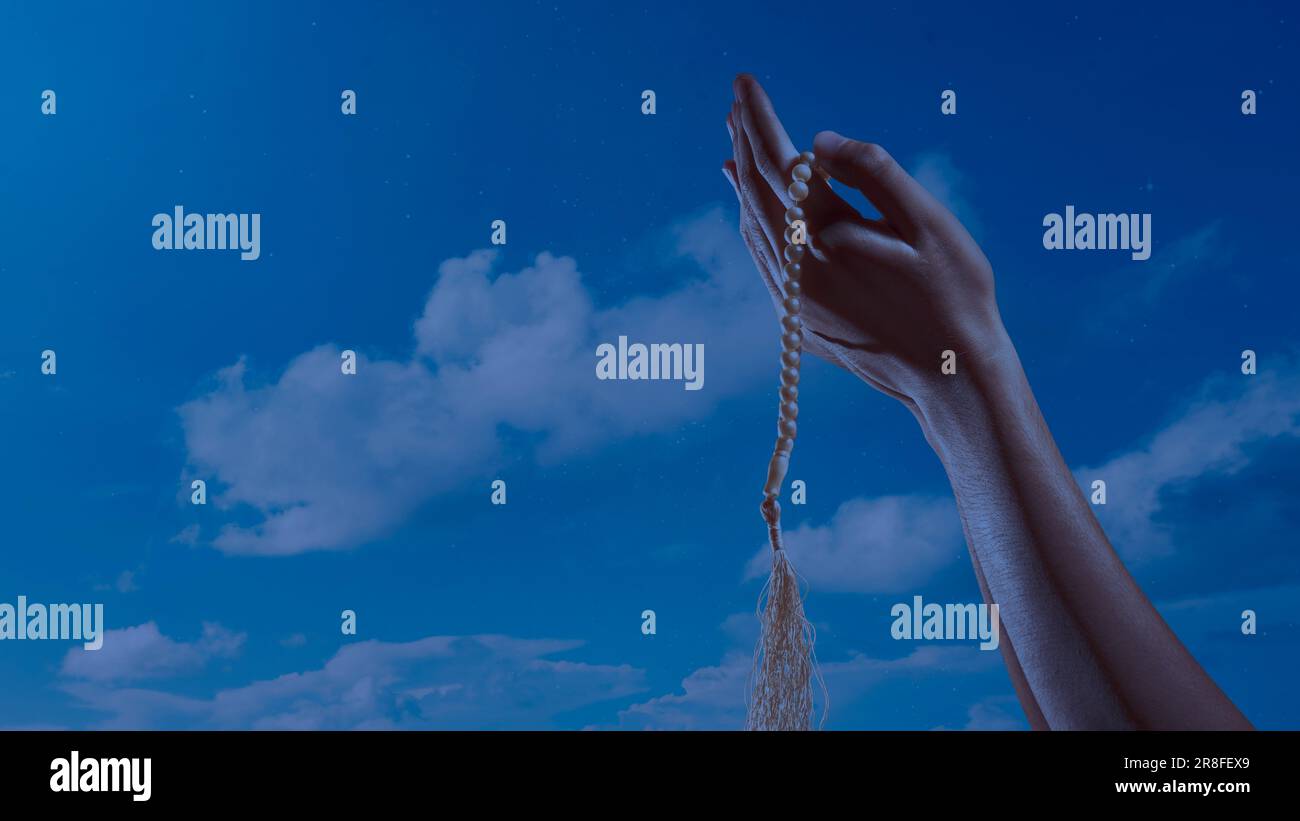 Muslim man praying with prayer beads in his hands with the night scene ...