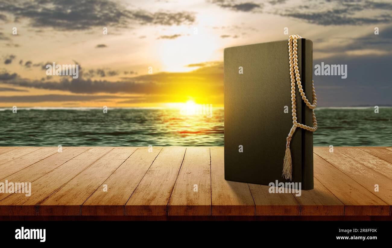 Quran and prayer beads on the wooden table with a sunset scene ...