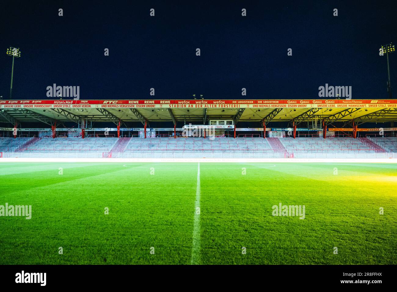 A soccer field illuminated by bright stadium stands and seating under ...