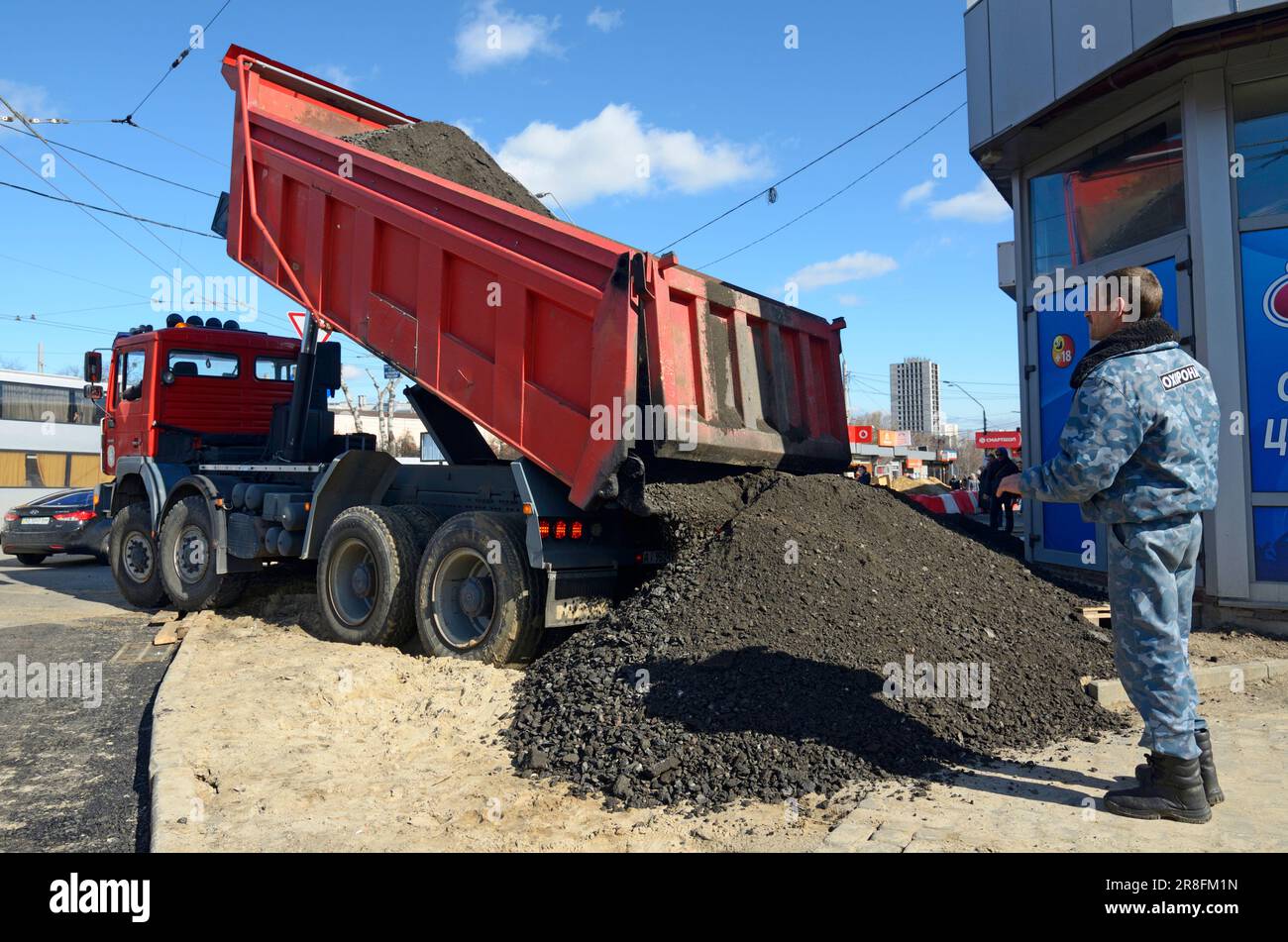 dump truck unloading bitumen for repairing pavement on a street, man ...