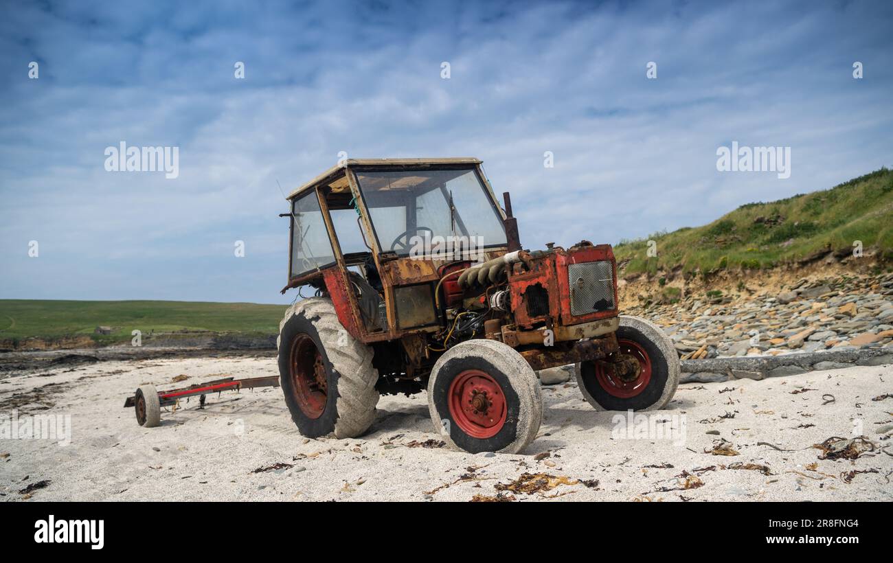 Rusty old tractor used to launch small fishing boats off a beach in ...
