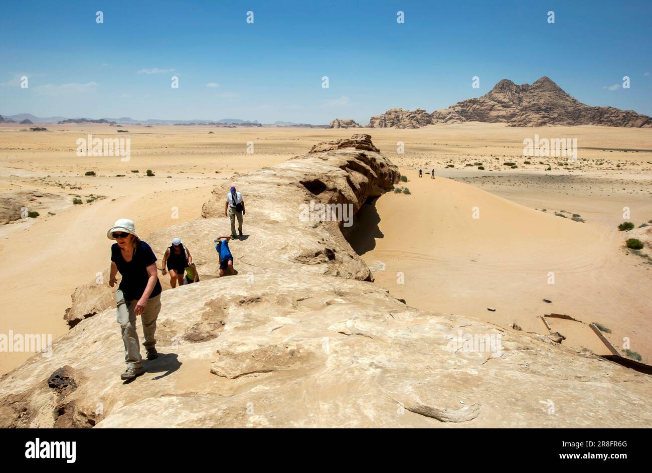 Tourists climb on top of the natural arch known as the Bridge at Wadi ...