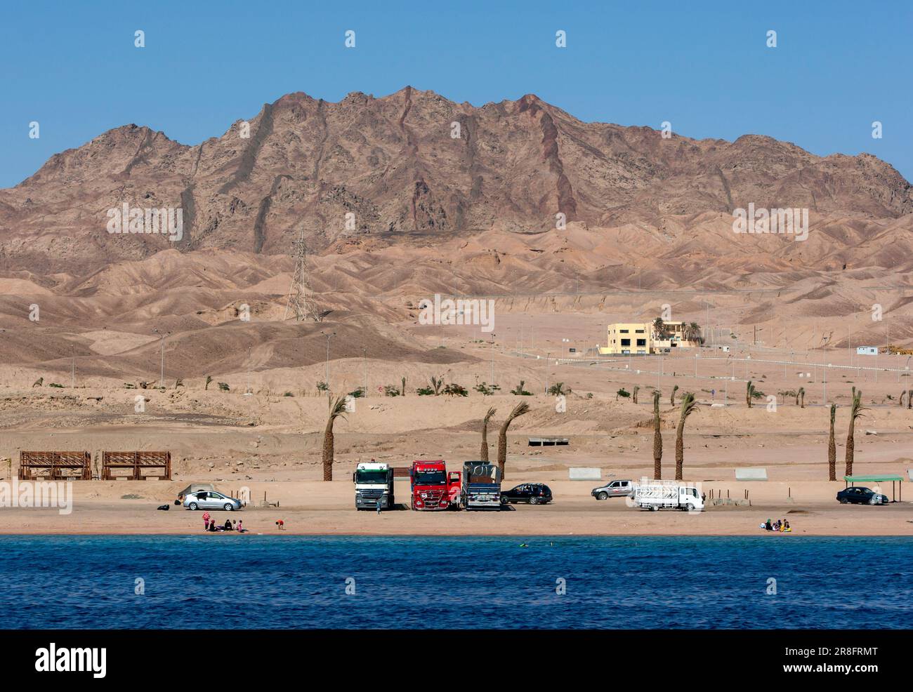 A row of trucks and cars sit on the bank of the Gulf of Aqaba in Jordan ...
