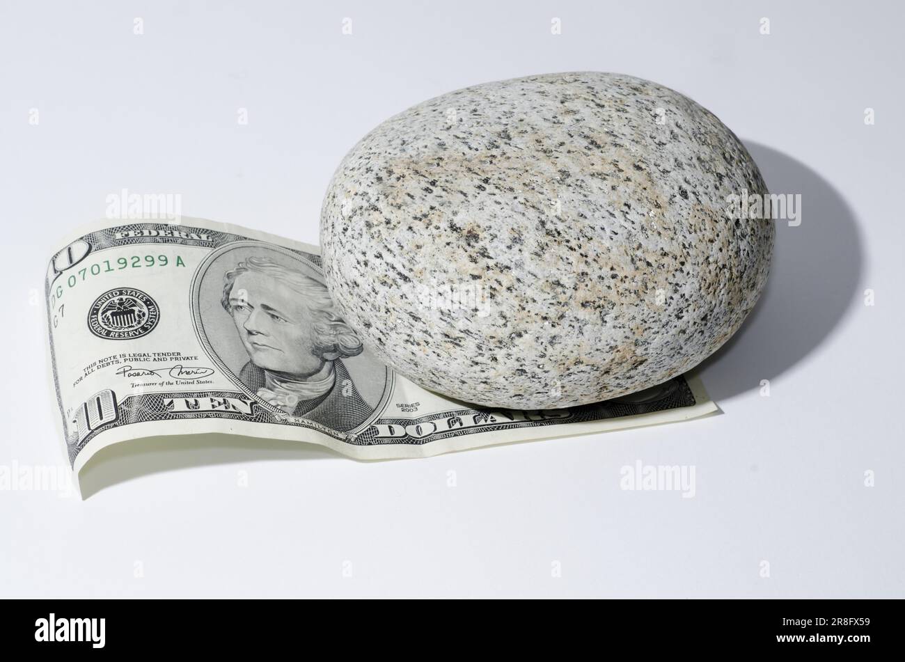 The Bill of Ten Dollar Lying Under a Stone with White Background Stock ...