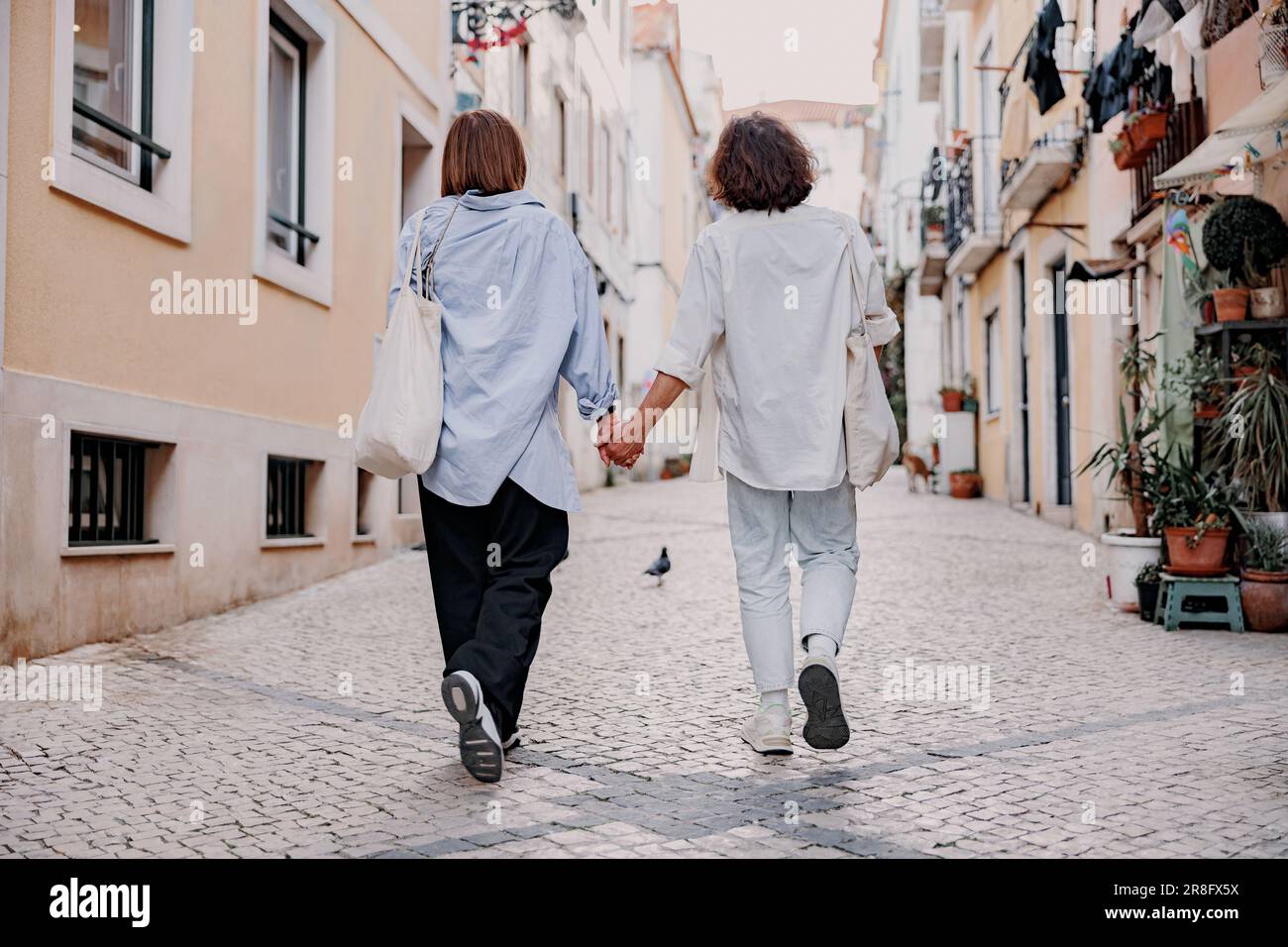 Back view of tourist couple hugging and walking on Lisbon street ...