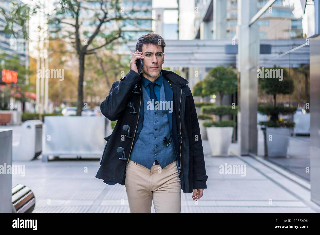 A handsome businessman talking on his cell phone while walking in the ...