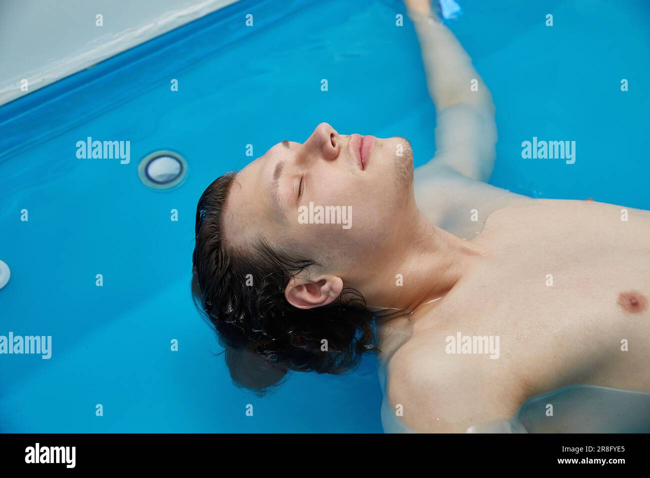Portrait of a man floating in a tank filled with thick salt water used ...