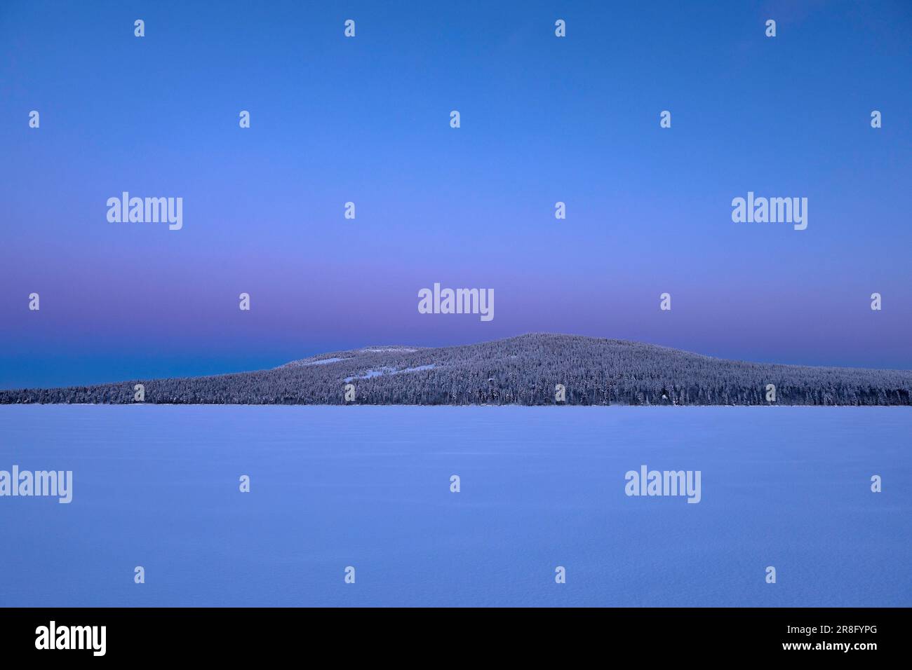 On Lake Pyhaejaervi, snow-covered trees, mountains and the day-night ...