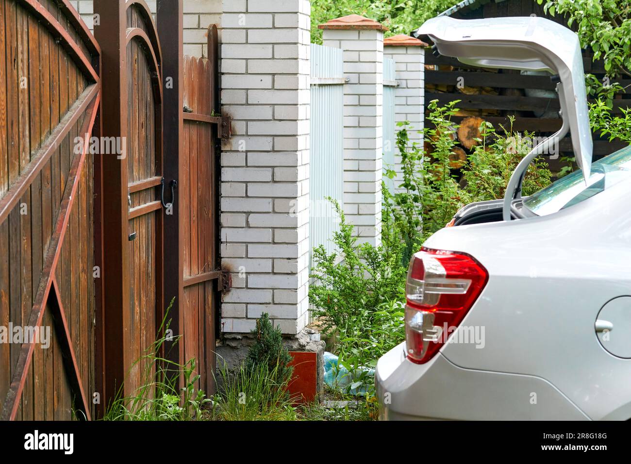 Back of the car with headlights and an open trunk. Brick fence. wooden ...