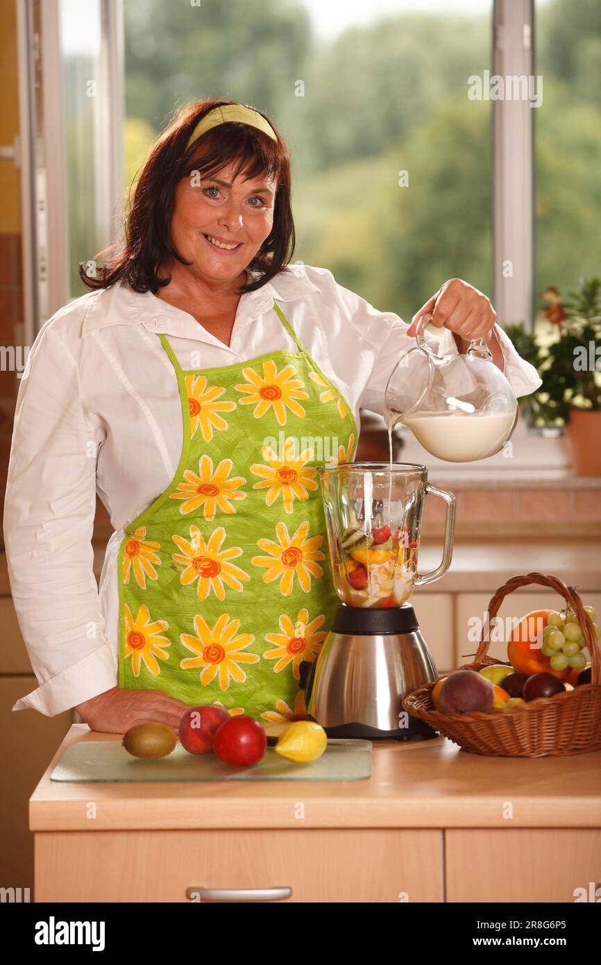 Woman pours milk to fruits in blender, prepare, stand mixer, mix, pours ...