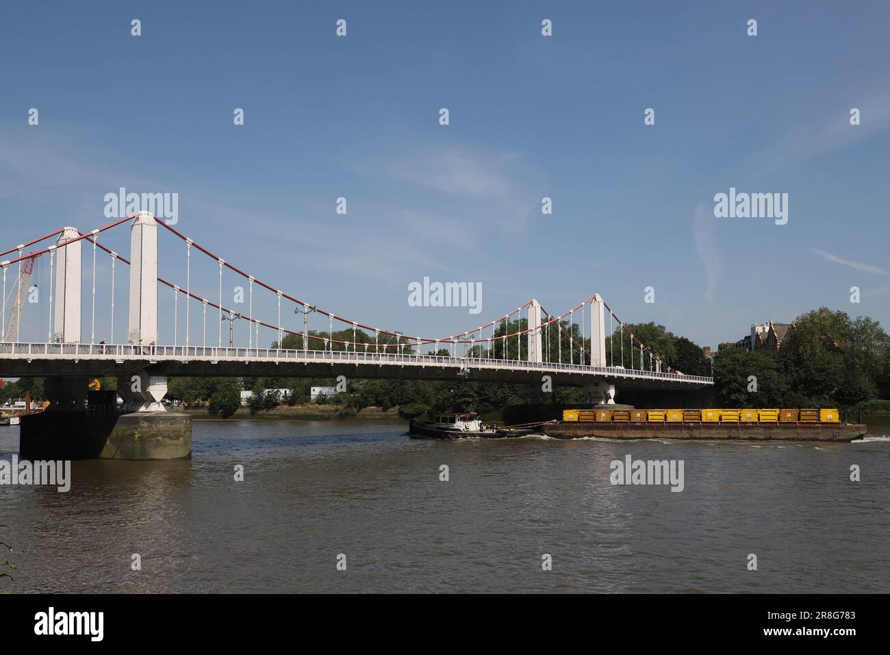 Boat towing barge along River Thames under Chelsea Bridge London UK ...