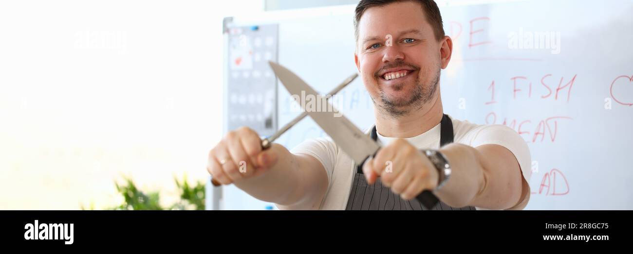 Smiling handsome male cook is holding sharp knife Stock Photo - Alamy