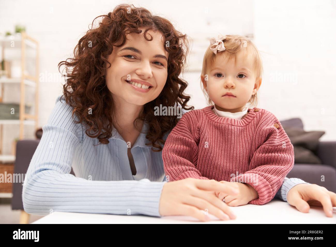 portrait of happy woman and child, curly working mother hugging baby ...