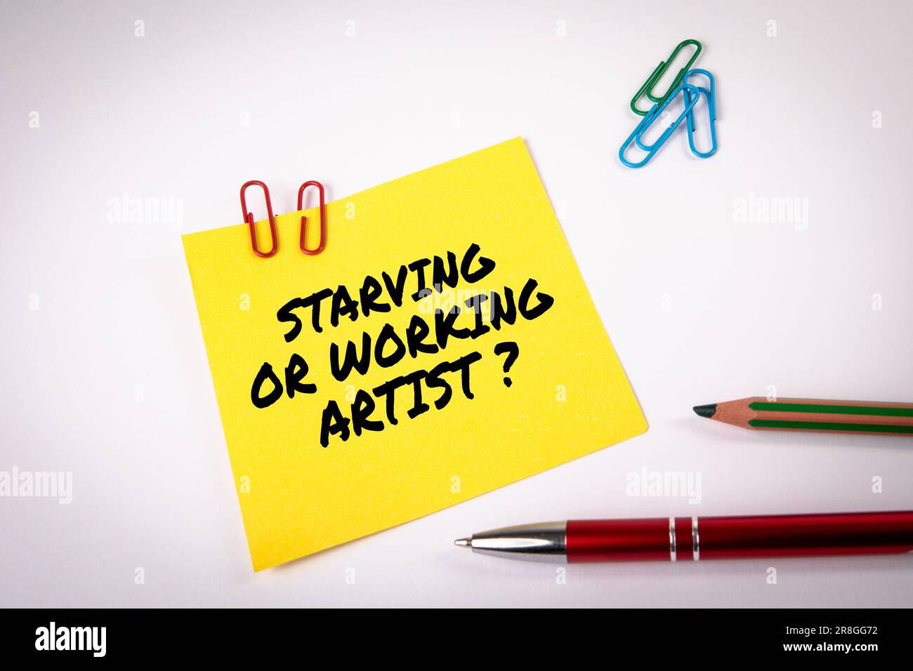 Starving or working artist. Yellow sticky note with text on a white ...