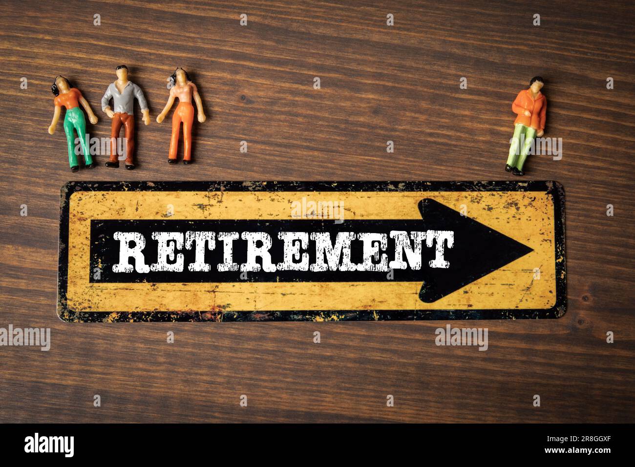 Retirement Concept. Arrow with text and miniature human figures on wood ...