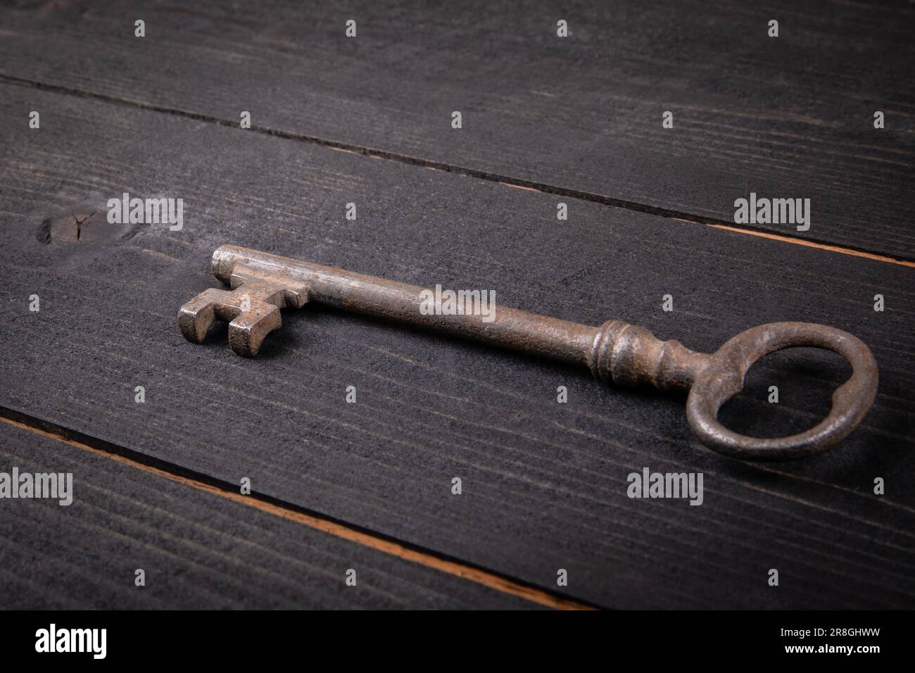 Old antique rusty key on dark wood texture background Stock Photo - Alamy
