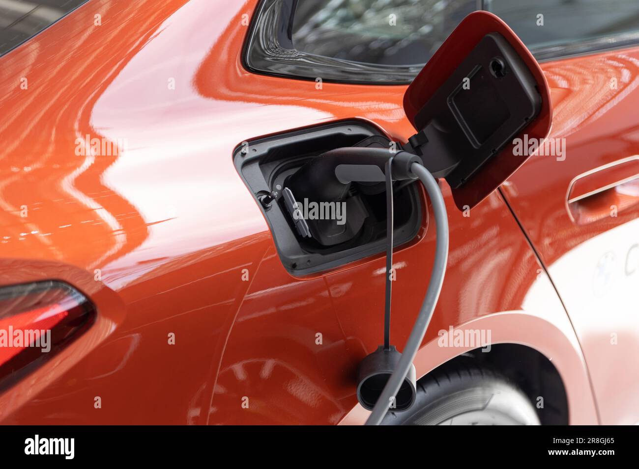 Orange electro car on charging at the EV charging station. Mid shot ...