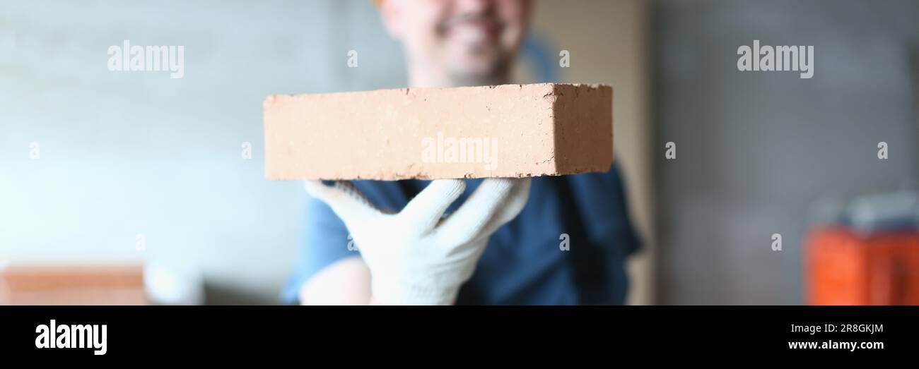 Master builder man holding red brick at construction site Stock Photo ...