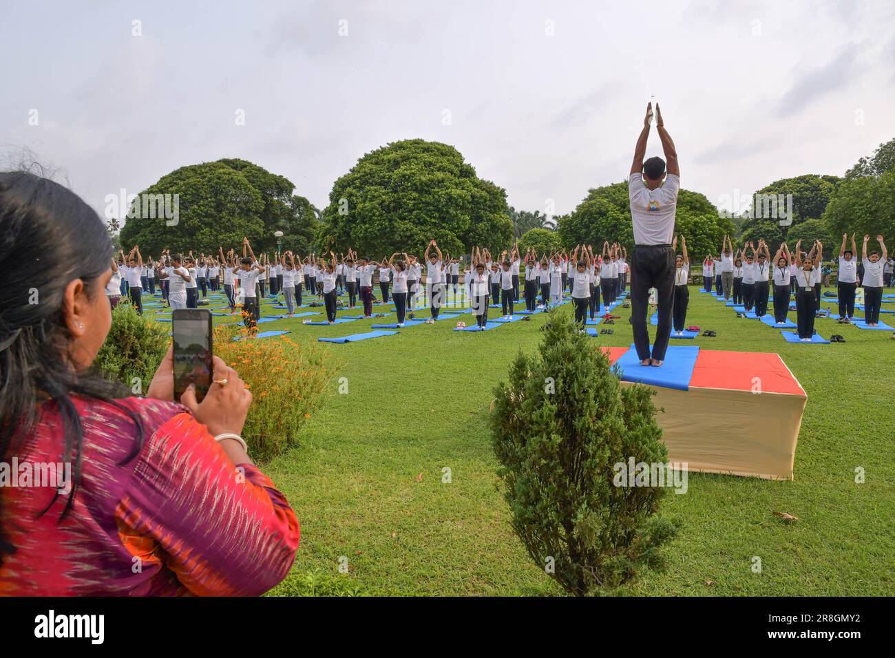 A visitor takes photos as students participate during the Yoga day at ...