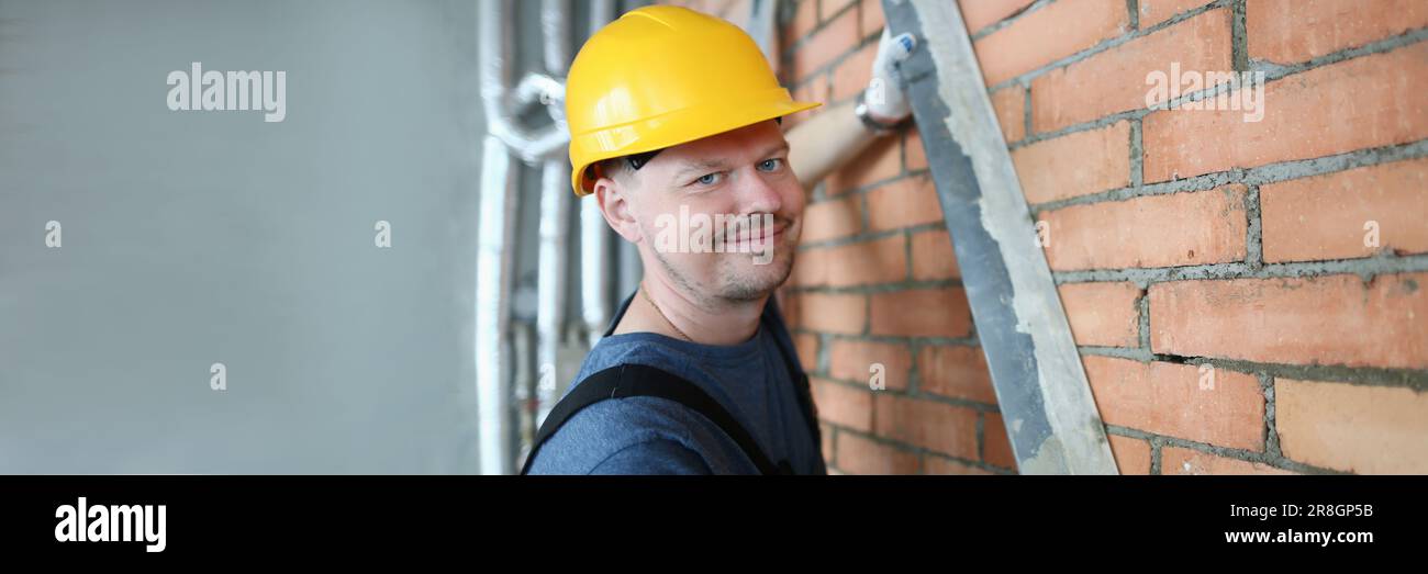 Male builder mason makes brickwork of walls and holds working tool ...
