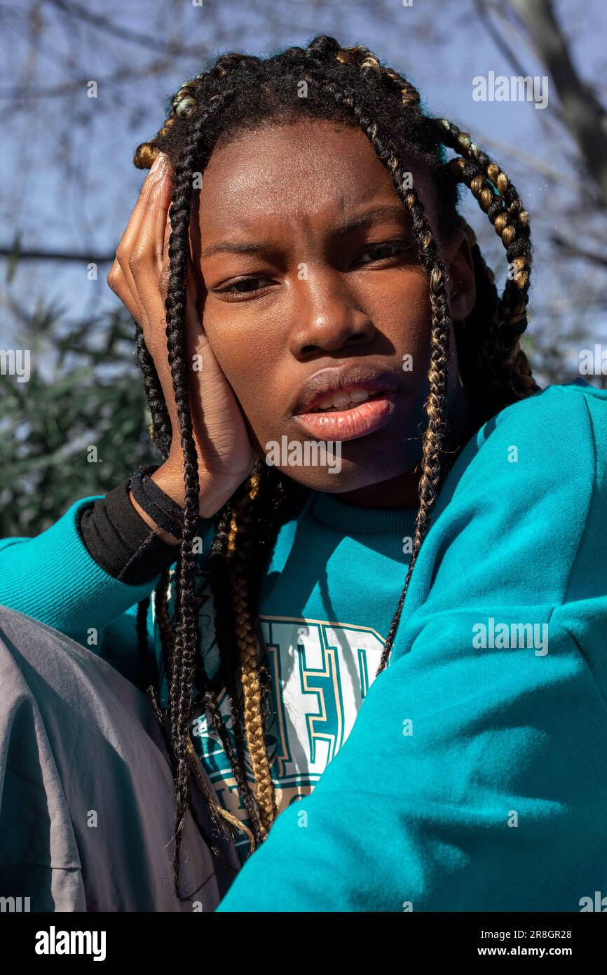 A young woman with her hand on her head, her dark brown hair styled ...