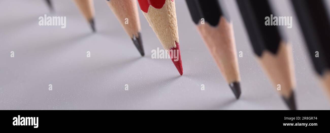 Sharp red pencil stands out from identical black pencils on gray ...