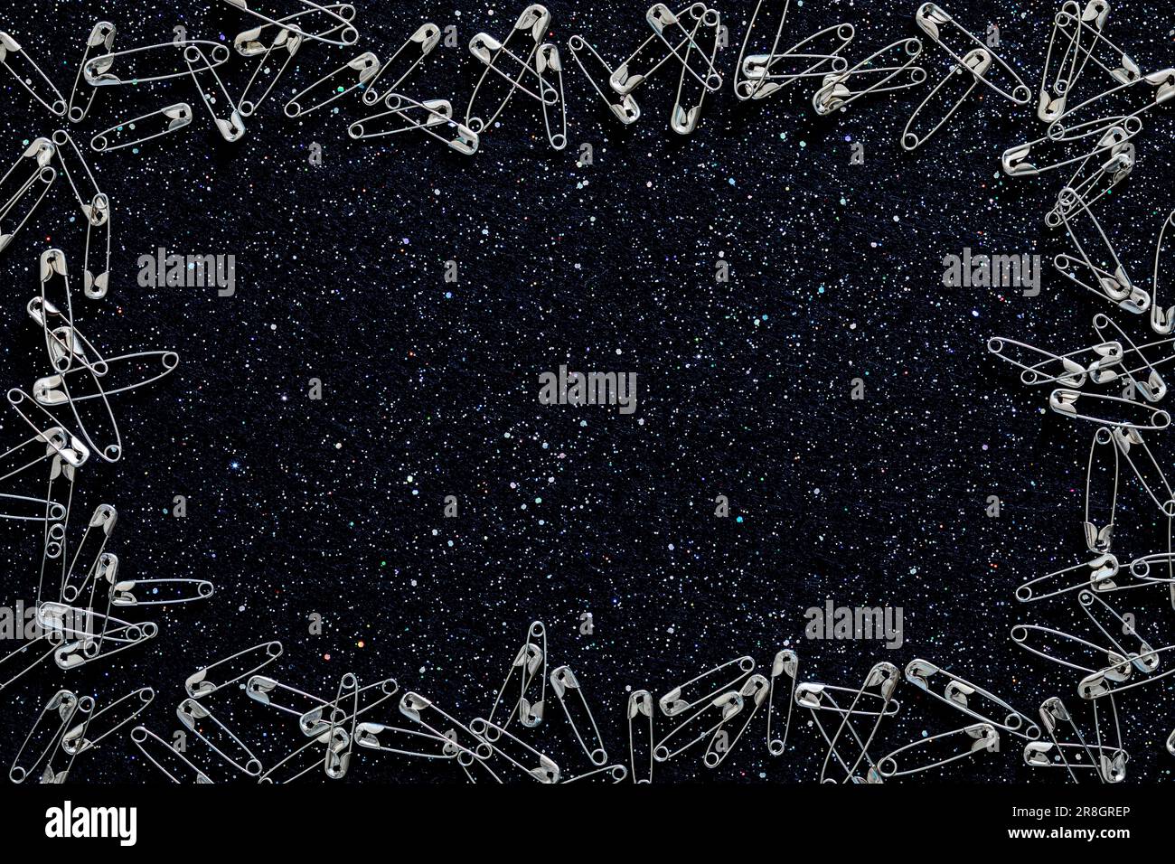Safety pins on black felt with colored glitter. Sewing texture ...
