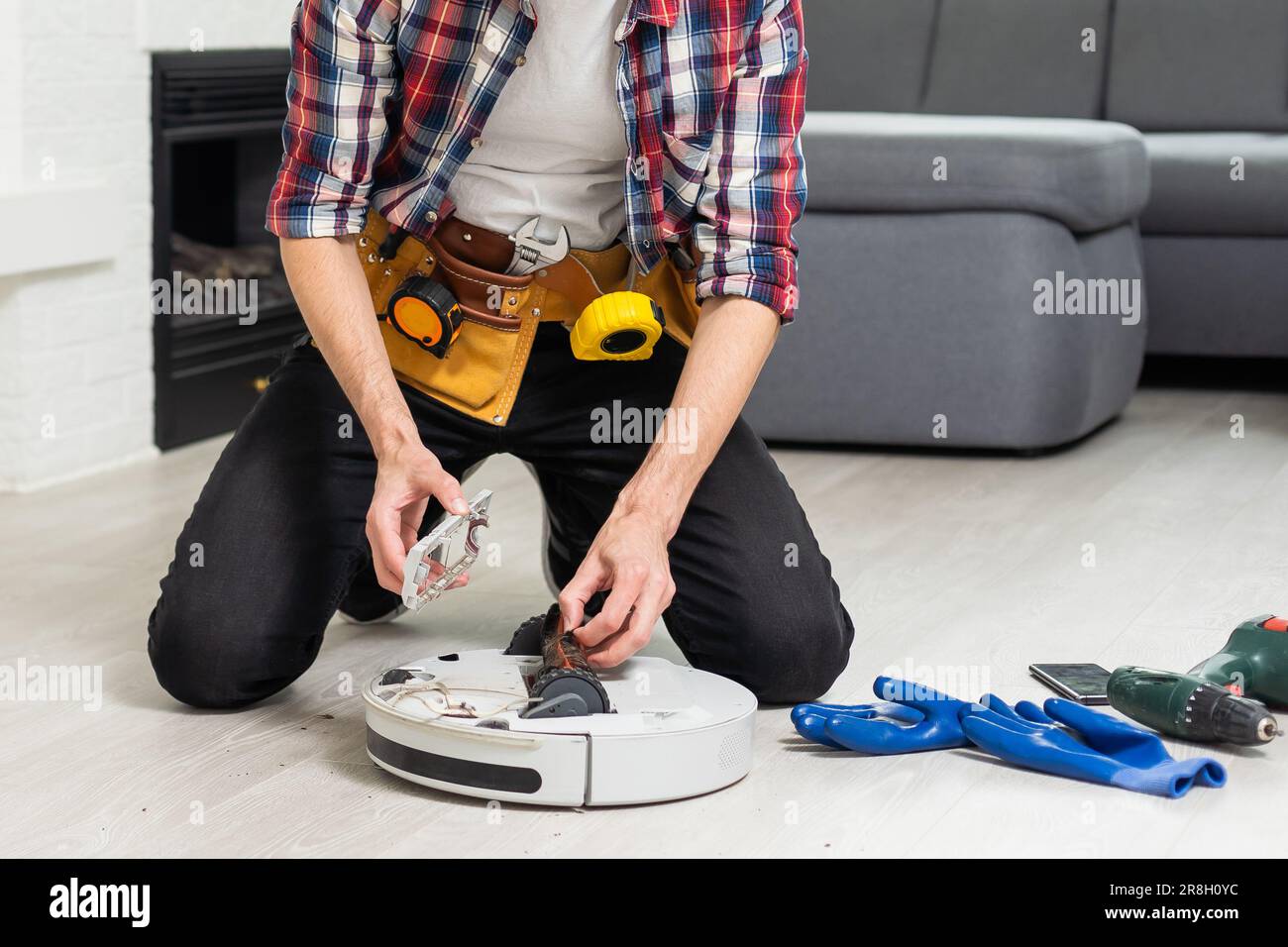 Caucasian young man doing white robot vacuum cleaner maintenance ...
