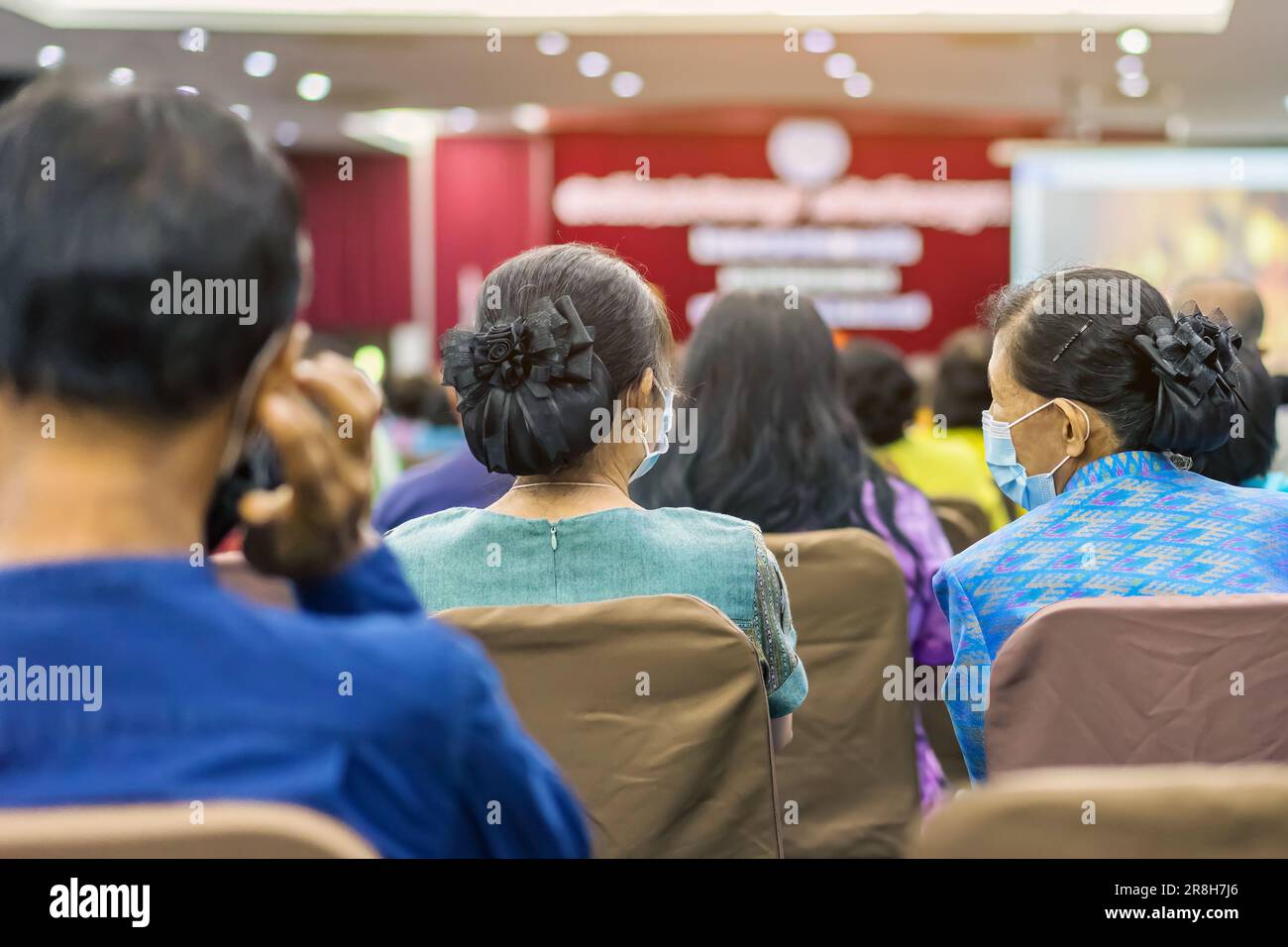 Back view of senior woman wear face mask attending and listening to the ...