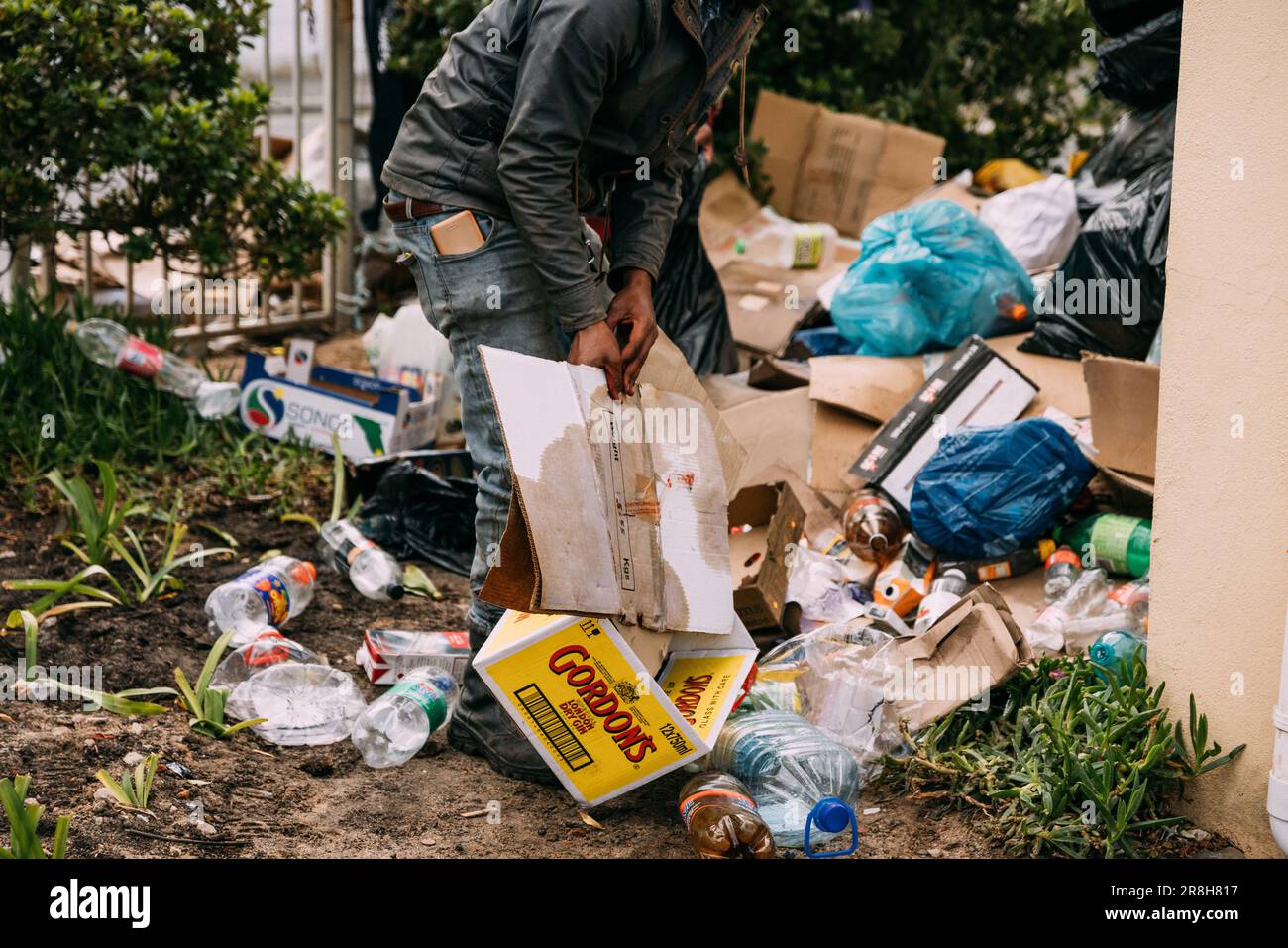 A low-angle view of a man cleaning up an abandoned dirty pile, Cape ...