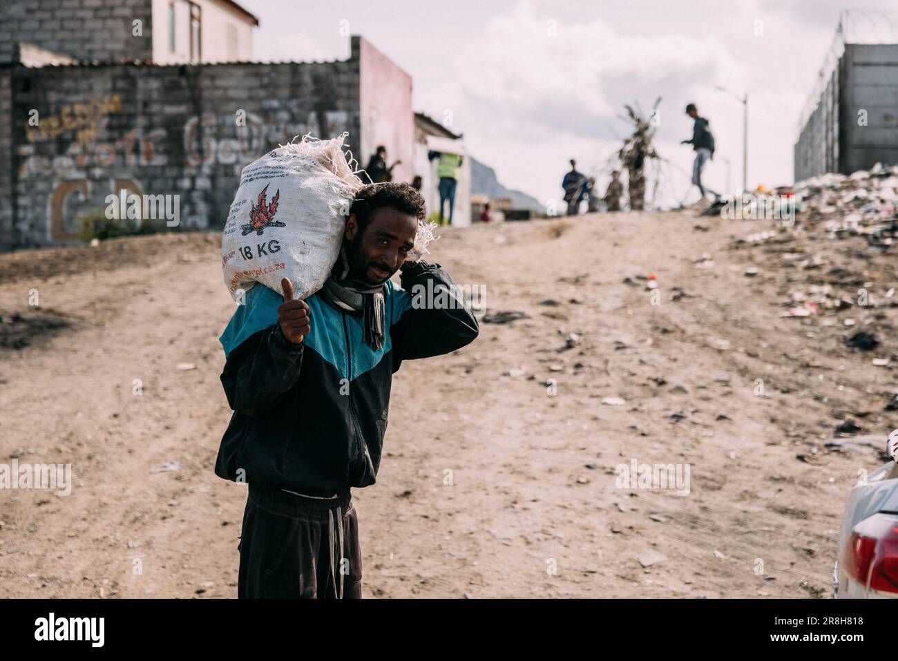 A South African male worker carrying a heavy load on his shoulder while ...