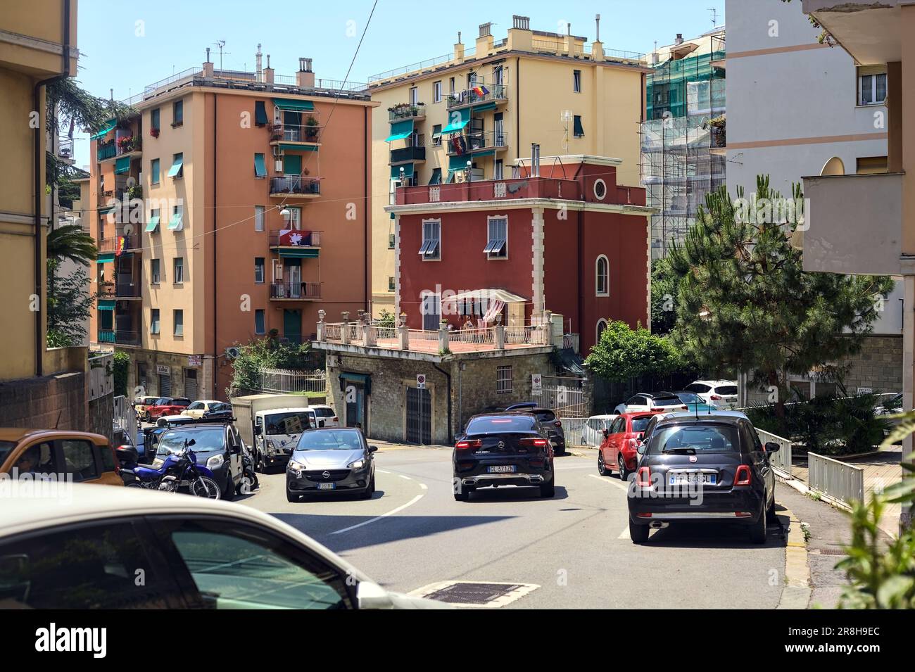 Sloping street with parked cars by its side and condominium bordering ...