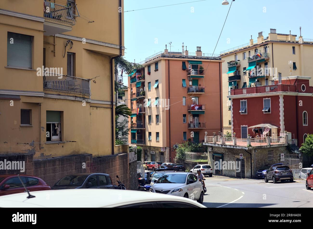 Sloping street with parked cars by its side and condominium bordering ...