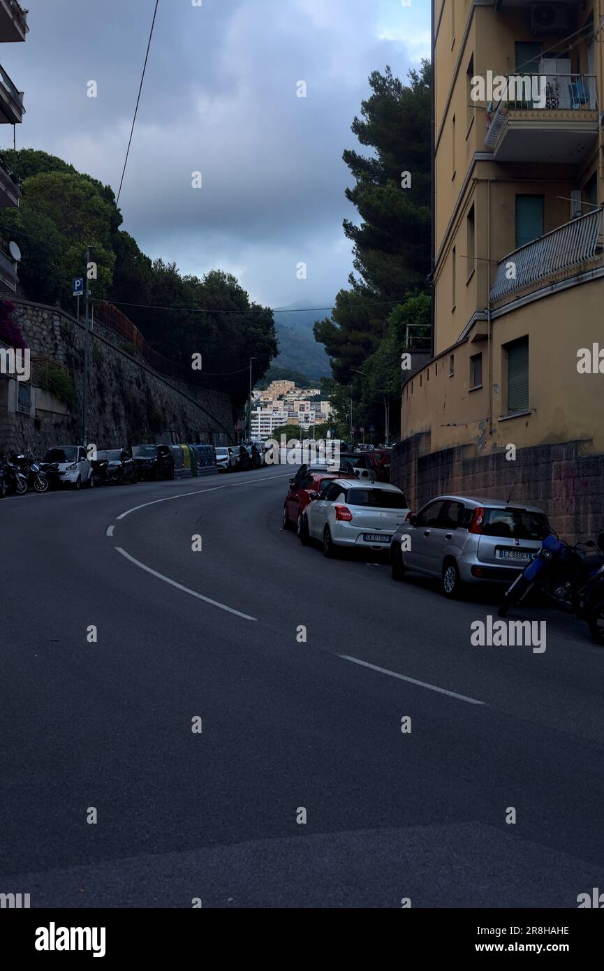 Sloping street with parked cars by its side and condominium bordering ...
