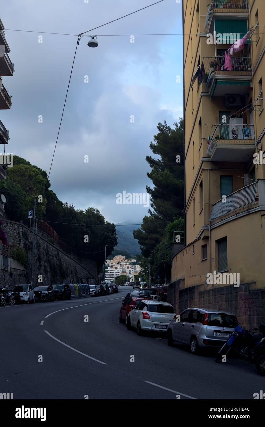 Sloping street with parked cars by its side and condominium bordering ...