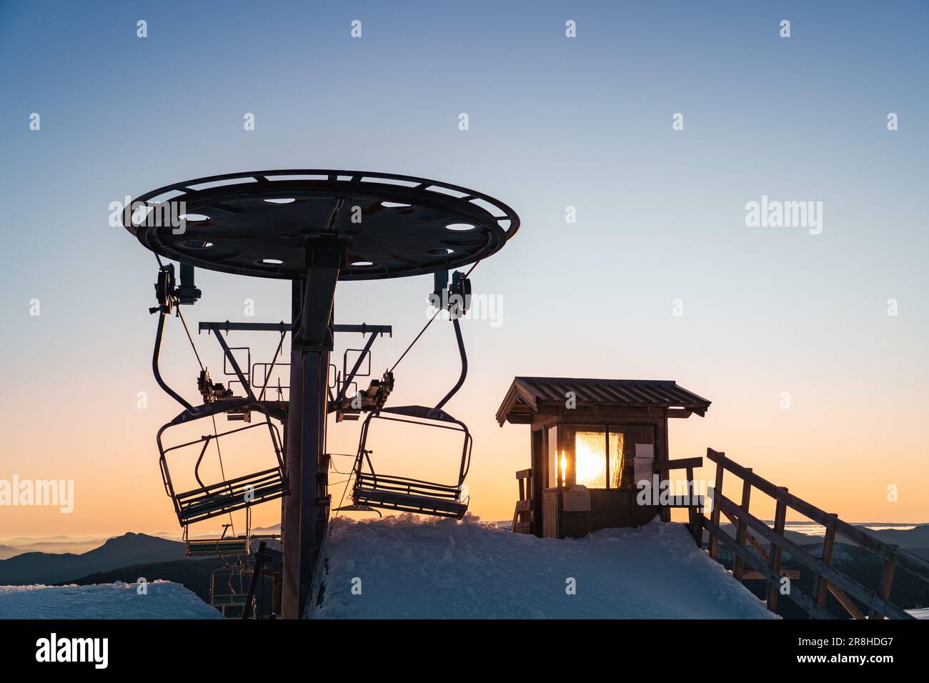 An outdoor chairlift with a backdrop of snow-covered mountains in the ...