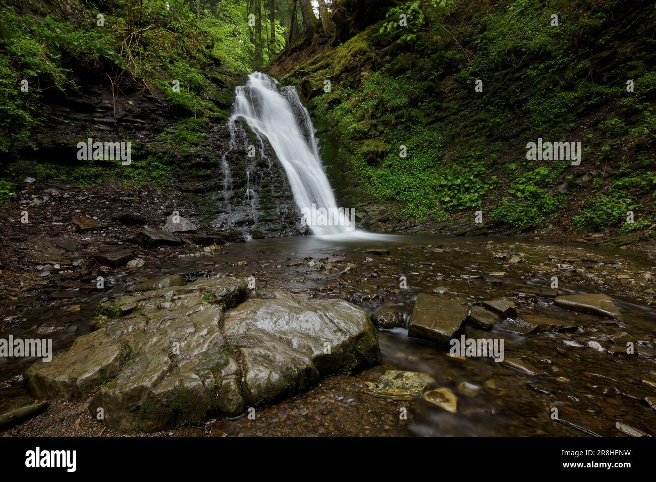 A waterfall in the midst of a magical wild nature, rocks covered with ...