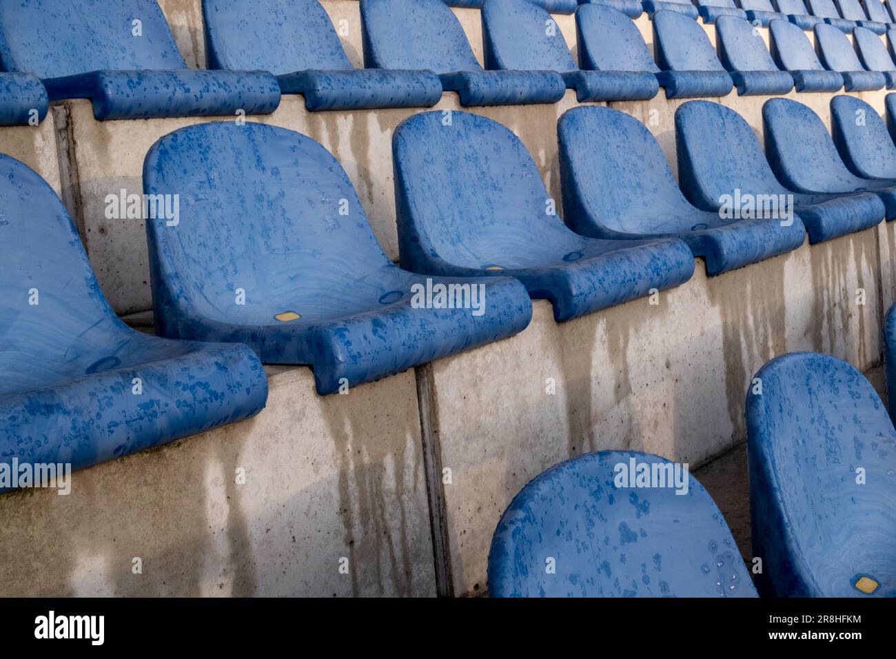 A line of blue plastic chairs are positioned along the wall of an ...