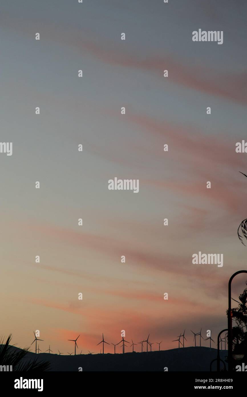 A breathtaking view of a dazzling pink and purple sunset with windmills ...