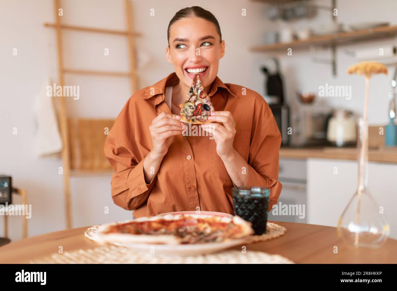 The joy of pizza. Excited lady enjoying eating tasty pizza holding and ...