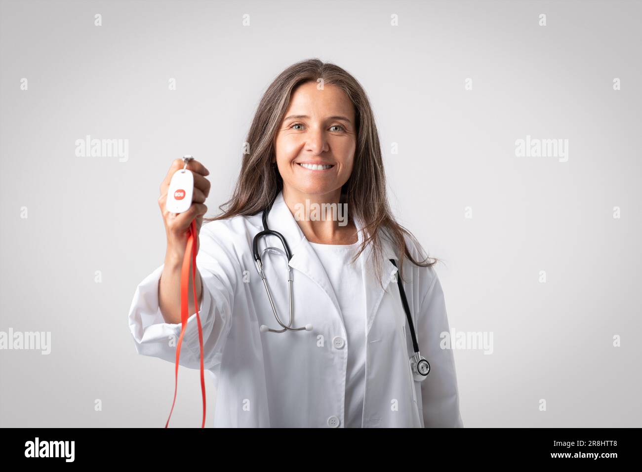 Happy senior woman therapist in white coat showing sos alarm button ...