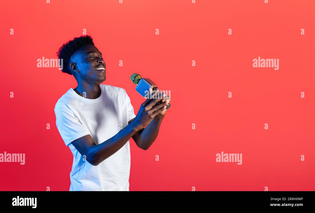 Happy young black guy holding mic, singing songs, copy space Stock ...